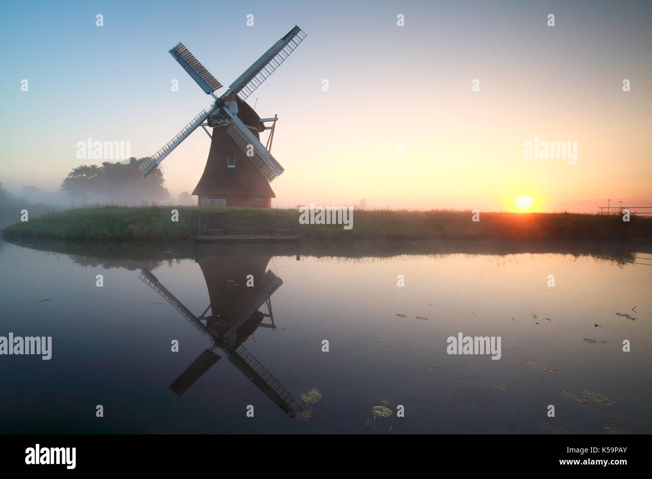 charming windmill by lake at misty sunrise Stock Photo - Alamy