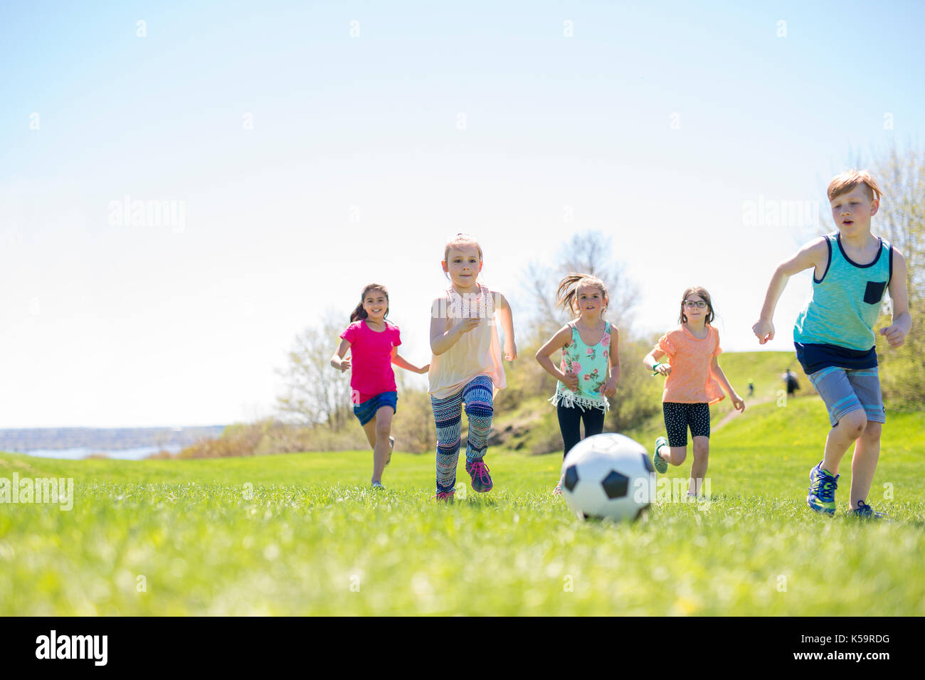 Boys and girls running towards football Stock Photo - Alamy