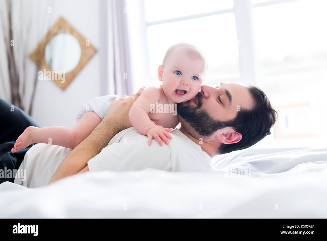 Young happy father playing with babyon bed Stock Photo - Alamy