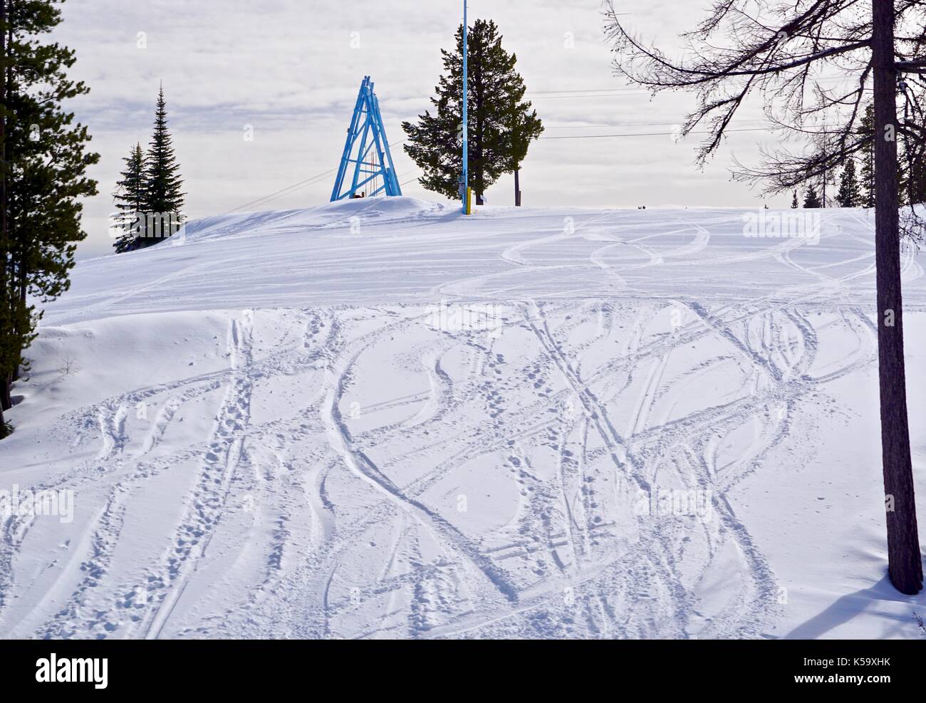 Ski hill with fresh snow and few tracks with blue ski lift structure ...