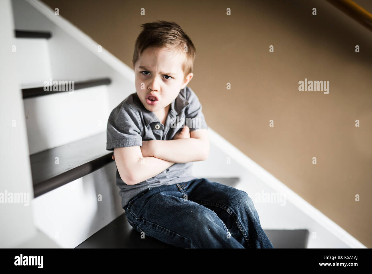 one sad little boy sitting on the stairs in house at the day time Stock ...