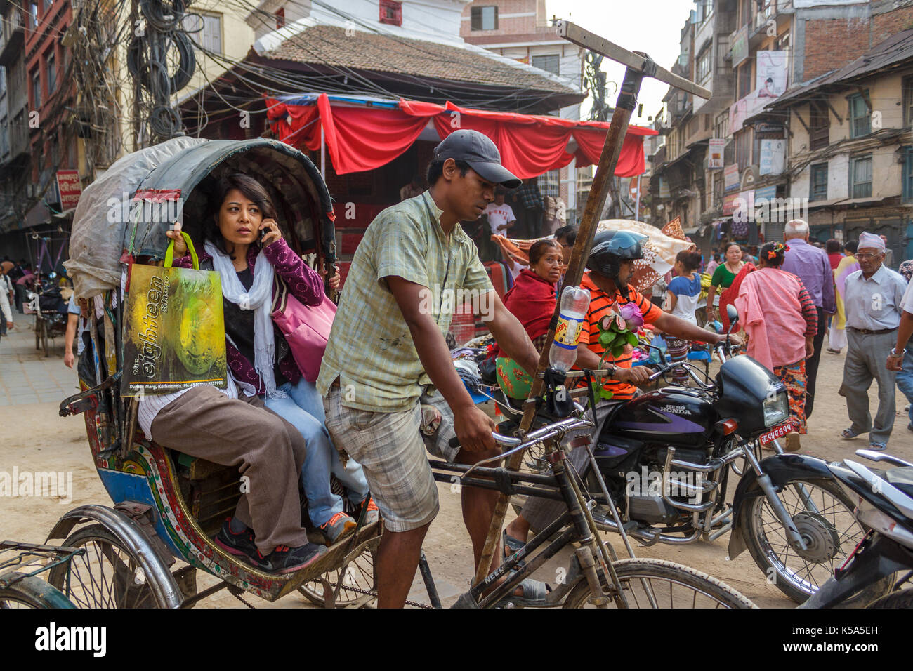 KATHMANDU, NEPAL - 9/26/2015: A woman rides a ricksha taxi through the ...