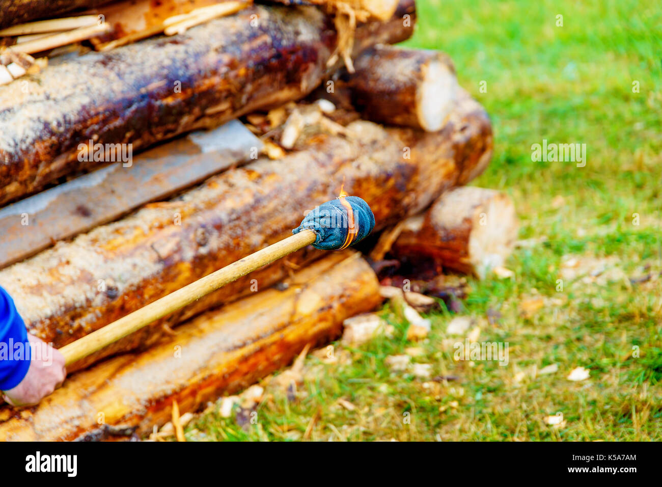 setting big bonfire made of logs on fire with torch Stock Photo - Alamy
