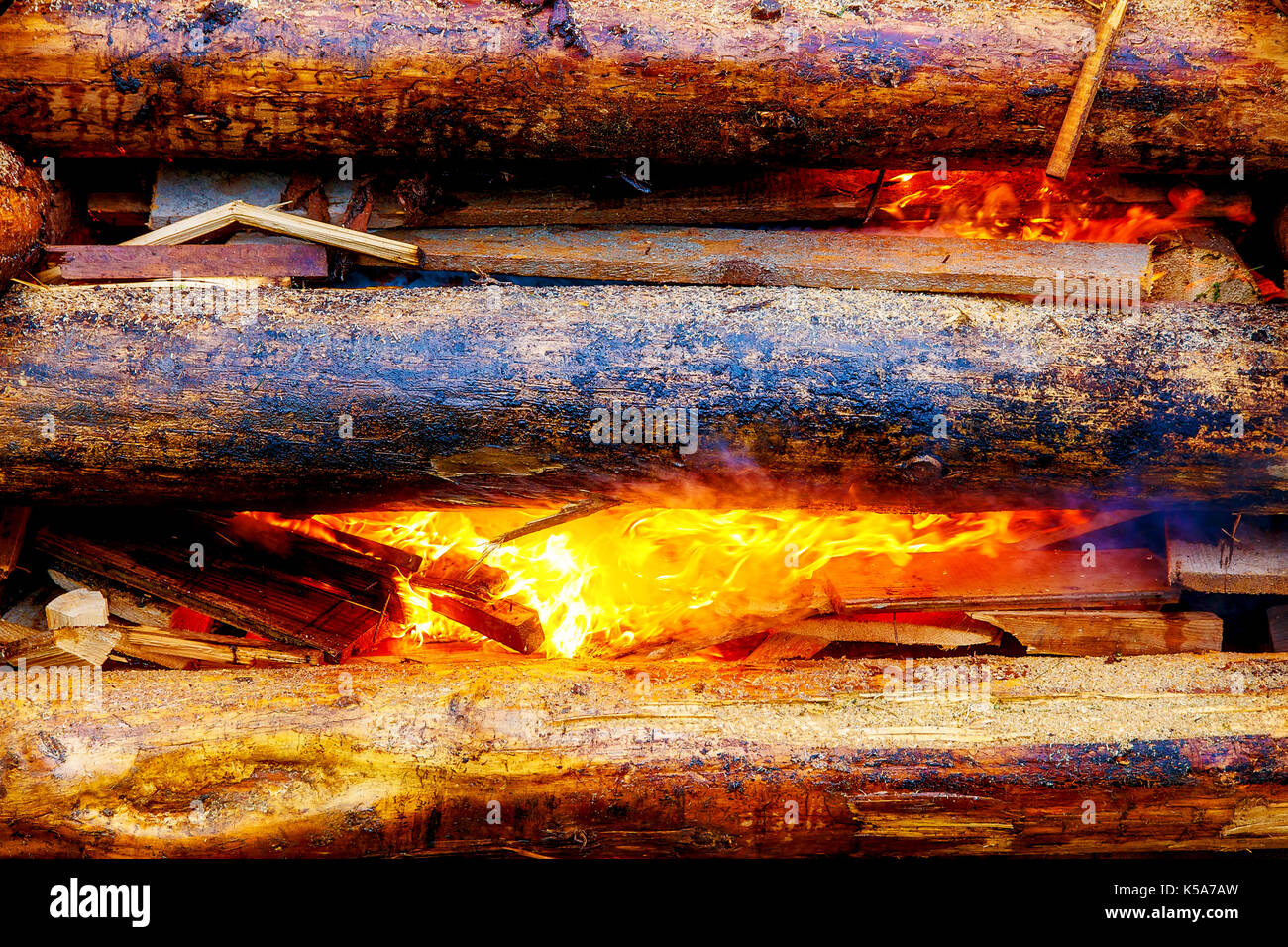 setting big bonfire made of logs on fire with torch Stock Photo - Alamy
