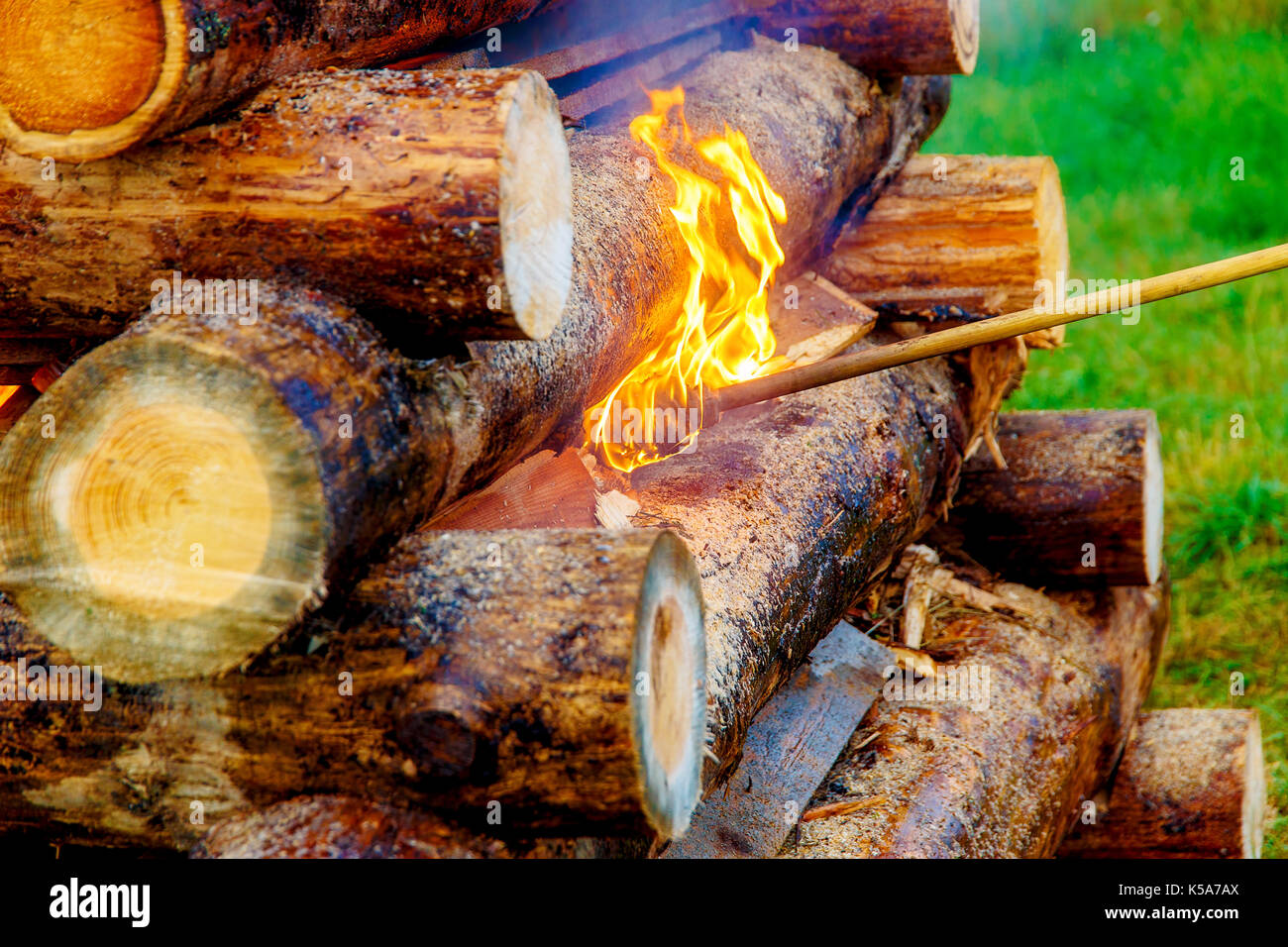 setting big bonfire made of logs on fire with torch Stock Photo - Alamy