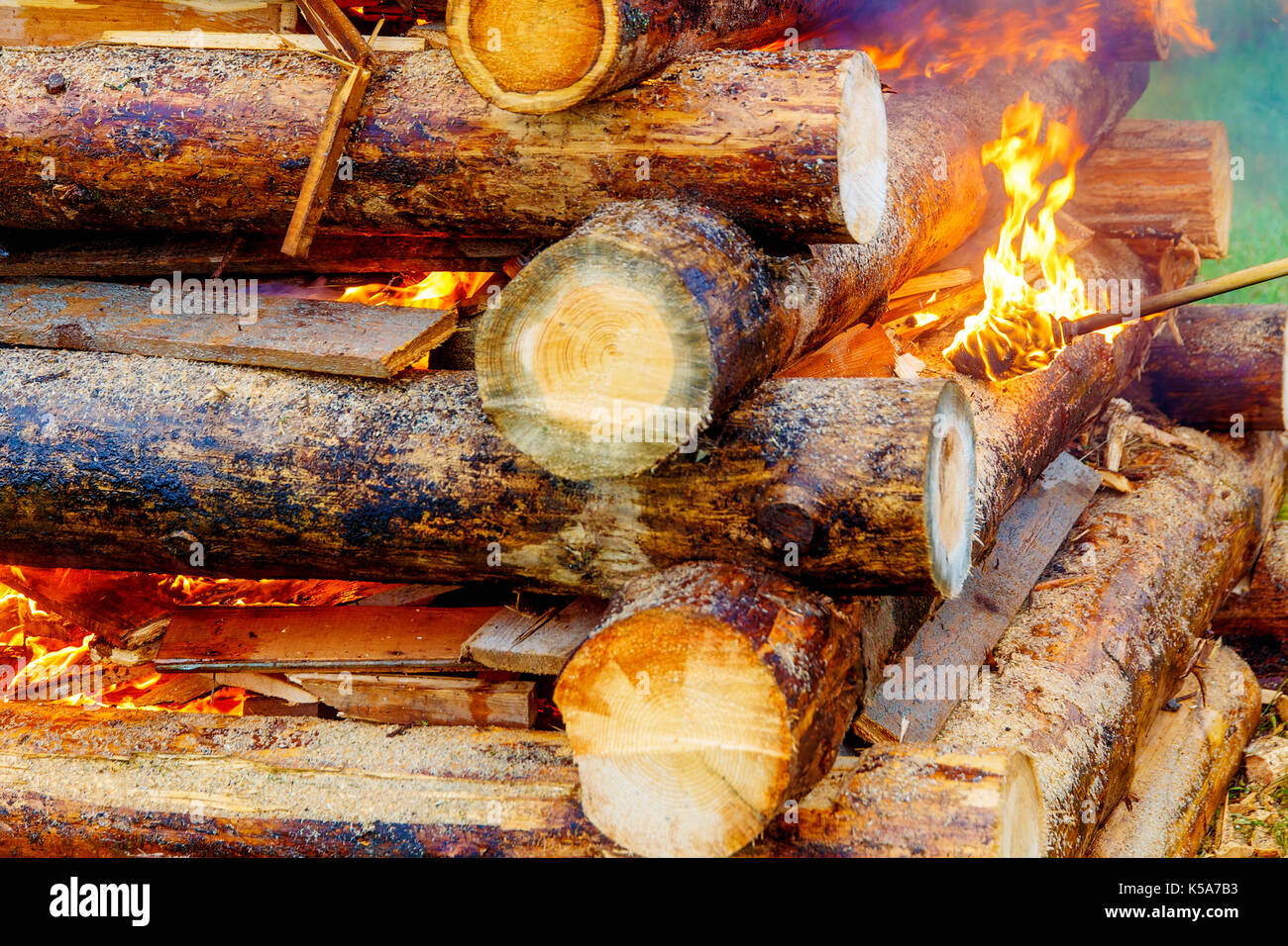 setting big bonfire made of logs on fire with torch Stock Photo - Alamy