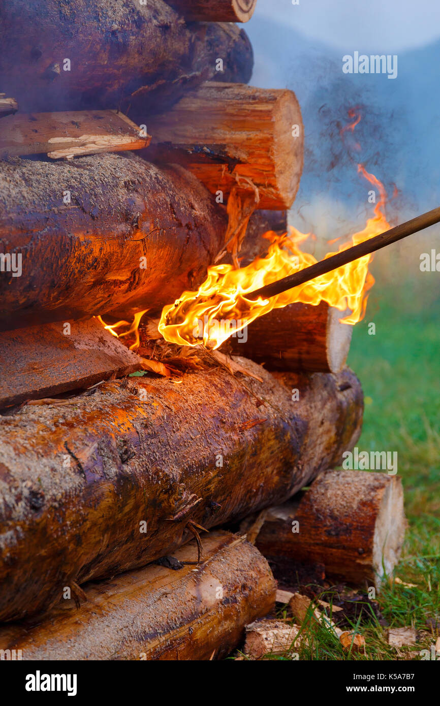 setting big bonfire made of logs on fire with torch Stock Photo - Alamy