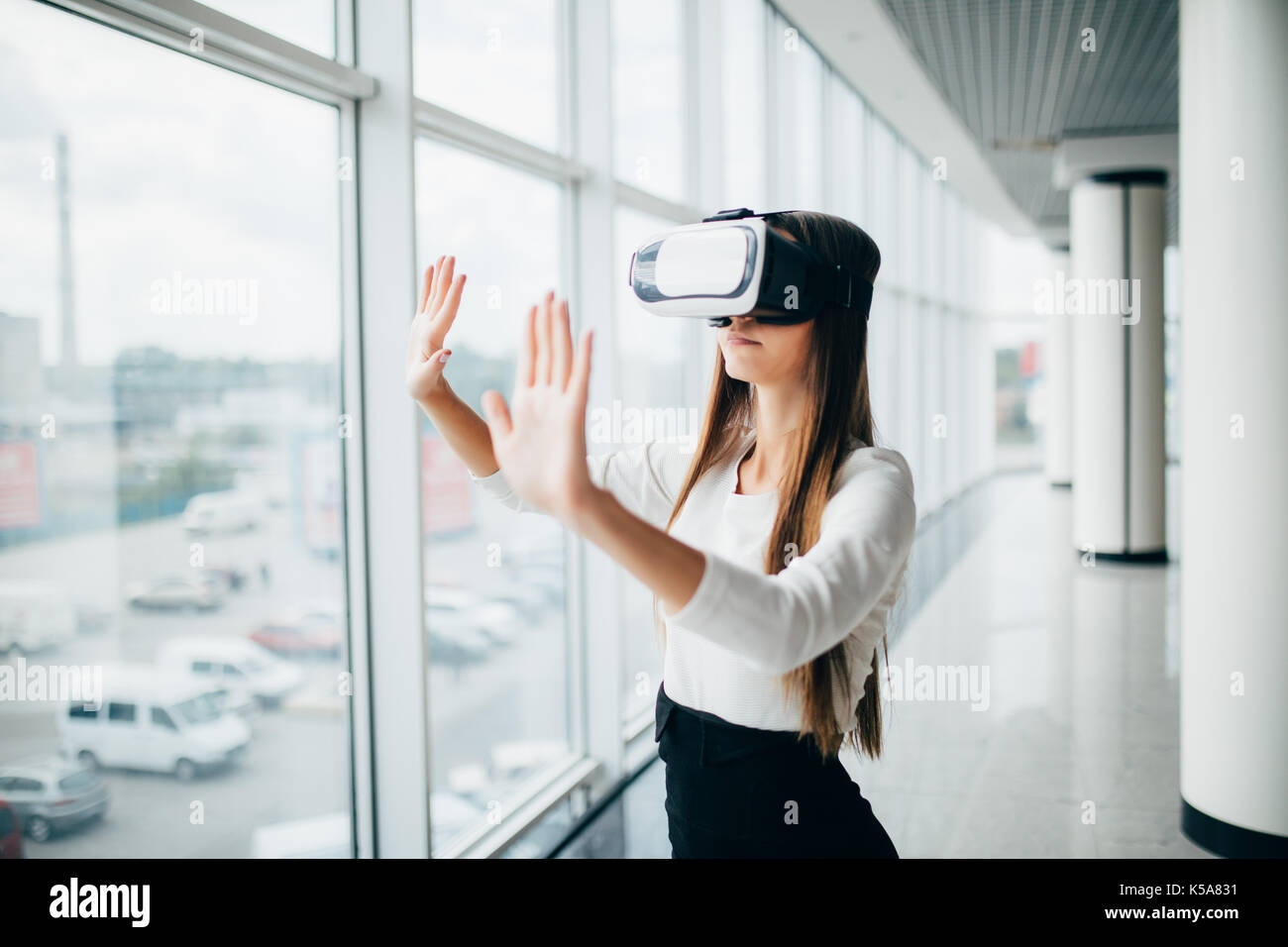 Beautiful girl using virtual reality glasses near bright window with ...