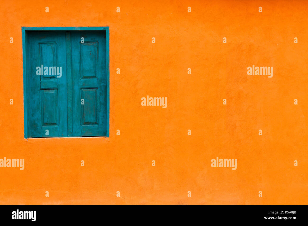 Vivid bright orange colour facade with blue-green window and large ...