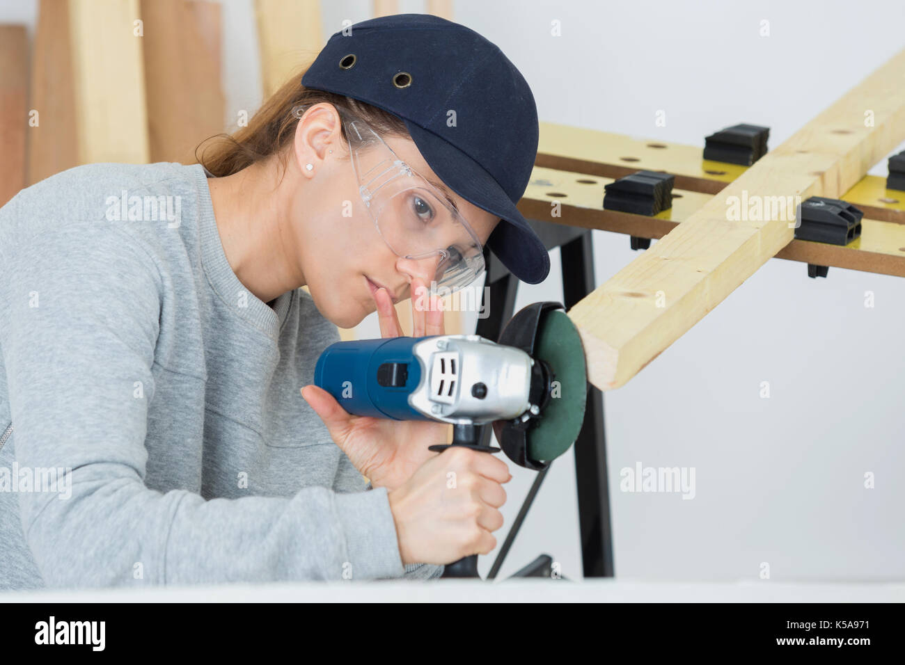 female worker in blue helmet cutting wood with angle grinder Stock ...
