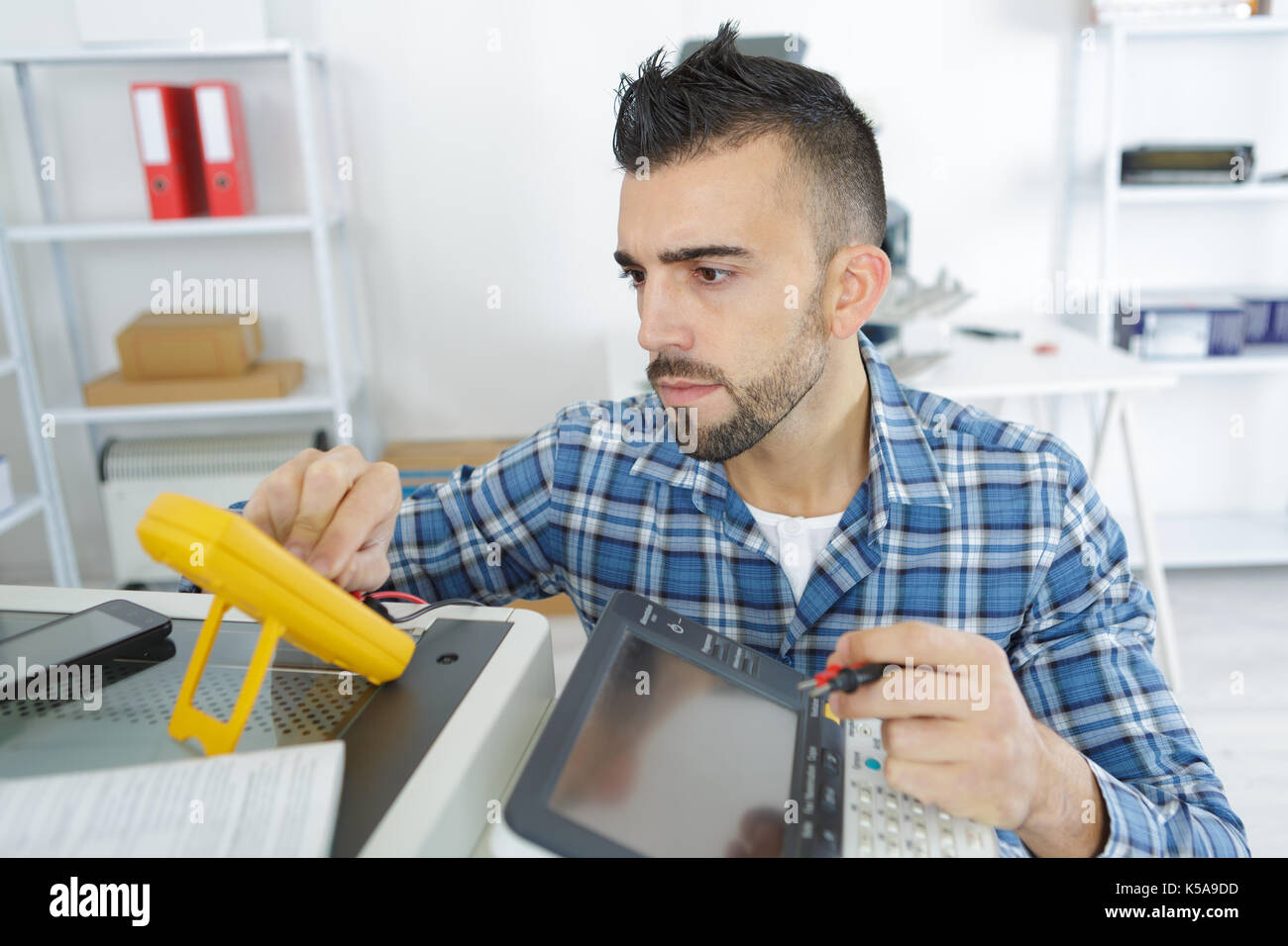 man doing maintenance repairs on printer using a multimeter Stock Photo ...