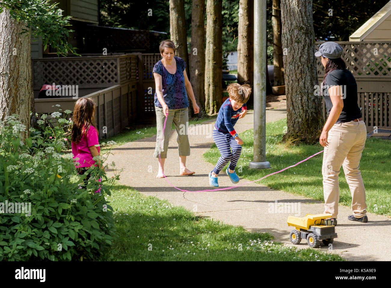 Young boy playing skipping rope game with adults Stock Photo - Alamy