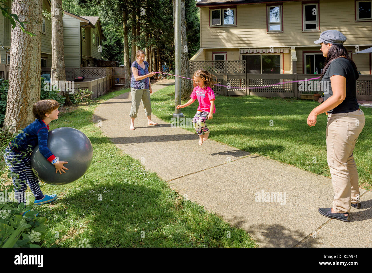 Young girl playing skipping rope game with adults Stock Photo - Alamy