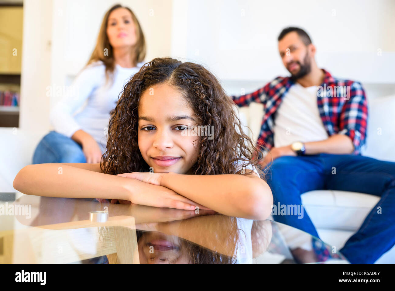 Portrait of a young teenage african girl leaning on a coffee table ...