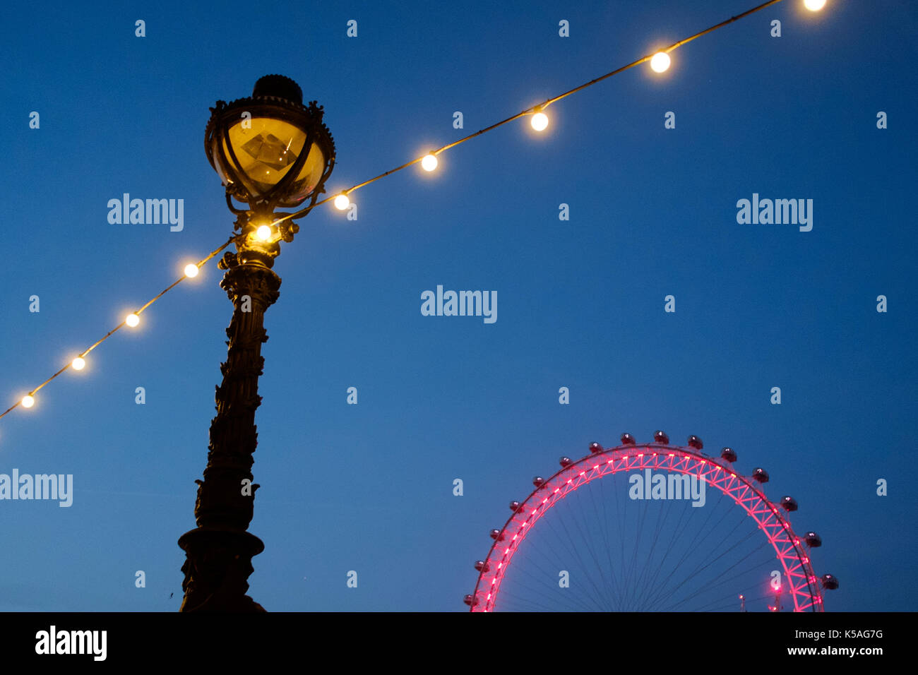 Street light by River Thames with backdrop of London Eye lit with Neon ...