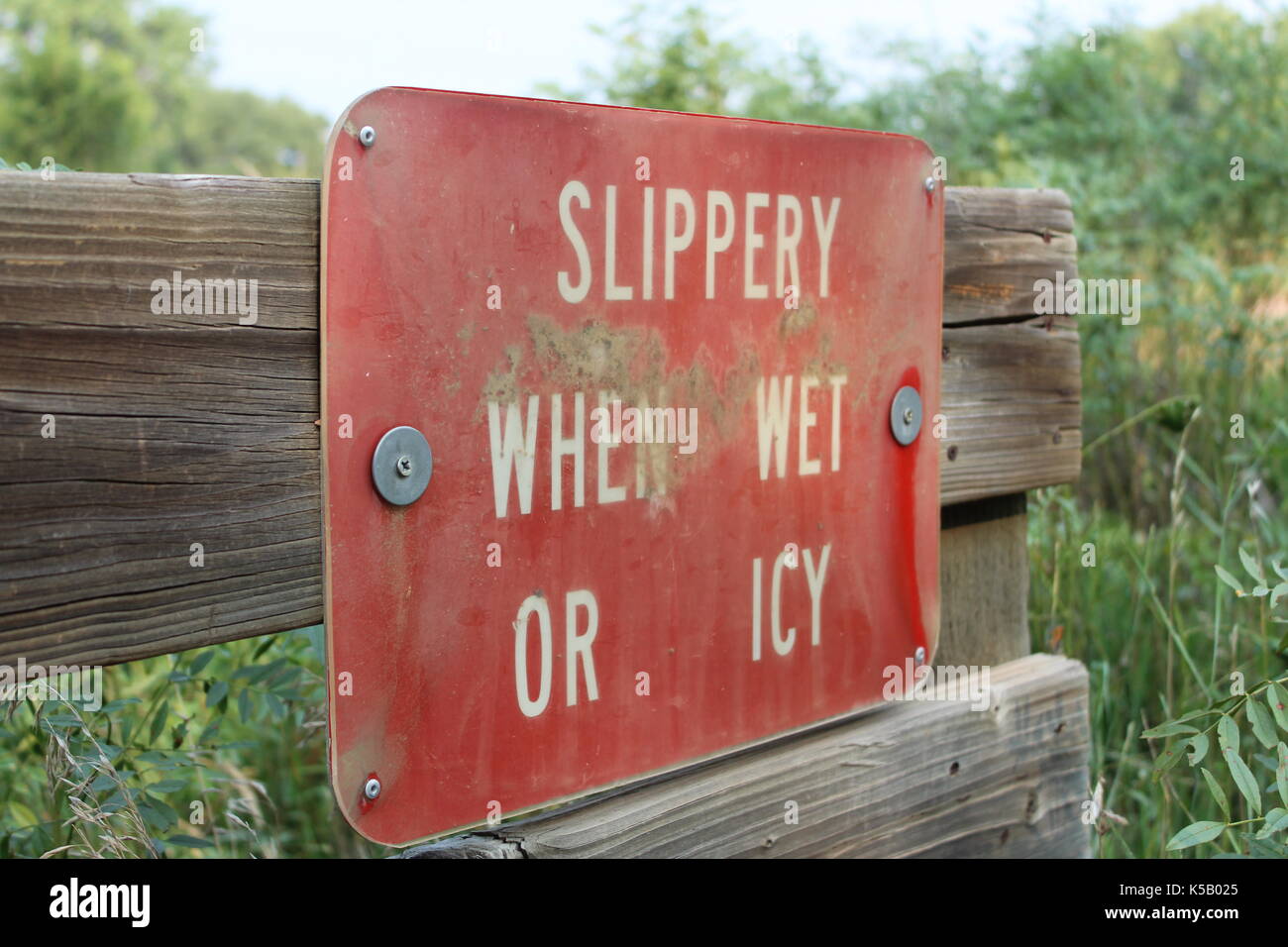 Slippery when wet or icy sign on bridge along walking trail in Fountain ...