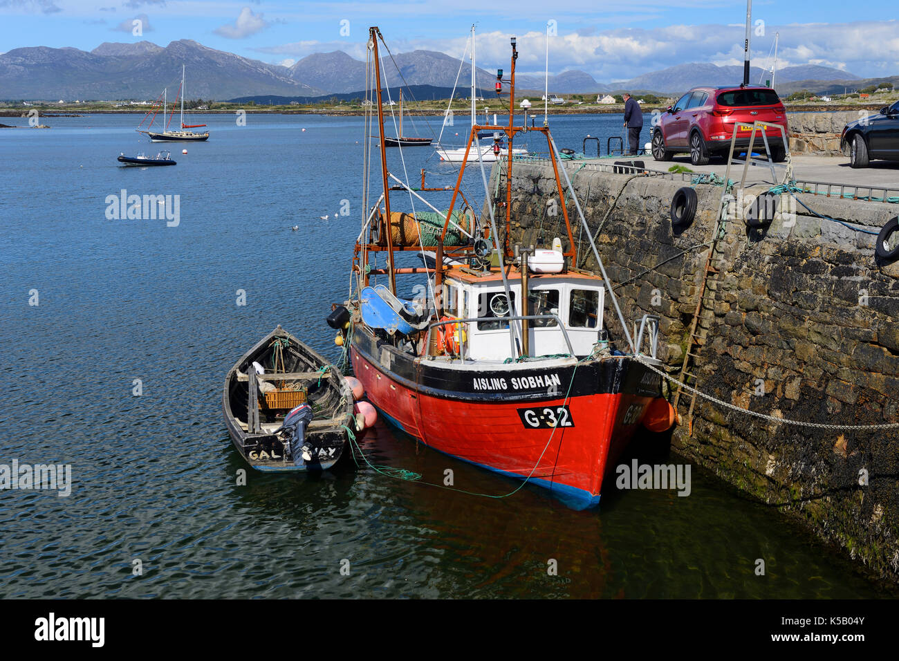 Fishing boat in Roundstone harbour with distant view of Twelve Bens ...