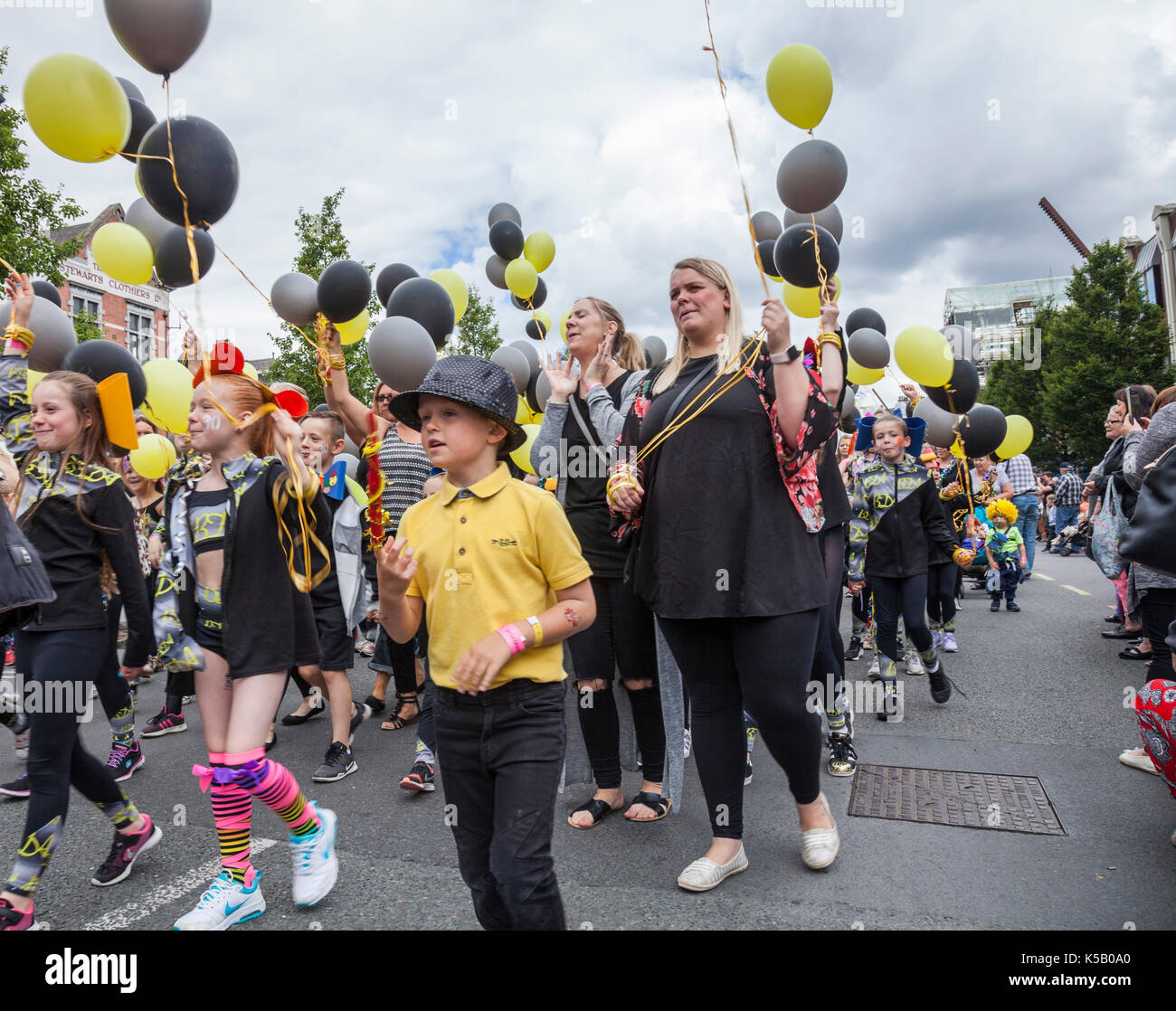 Women and children carrying coloured balloons walk down the High Street ...