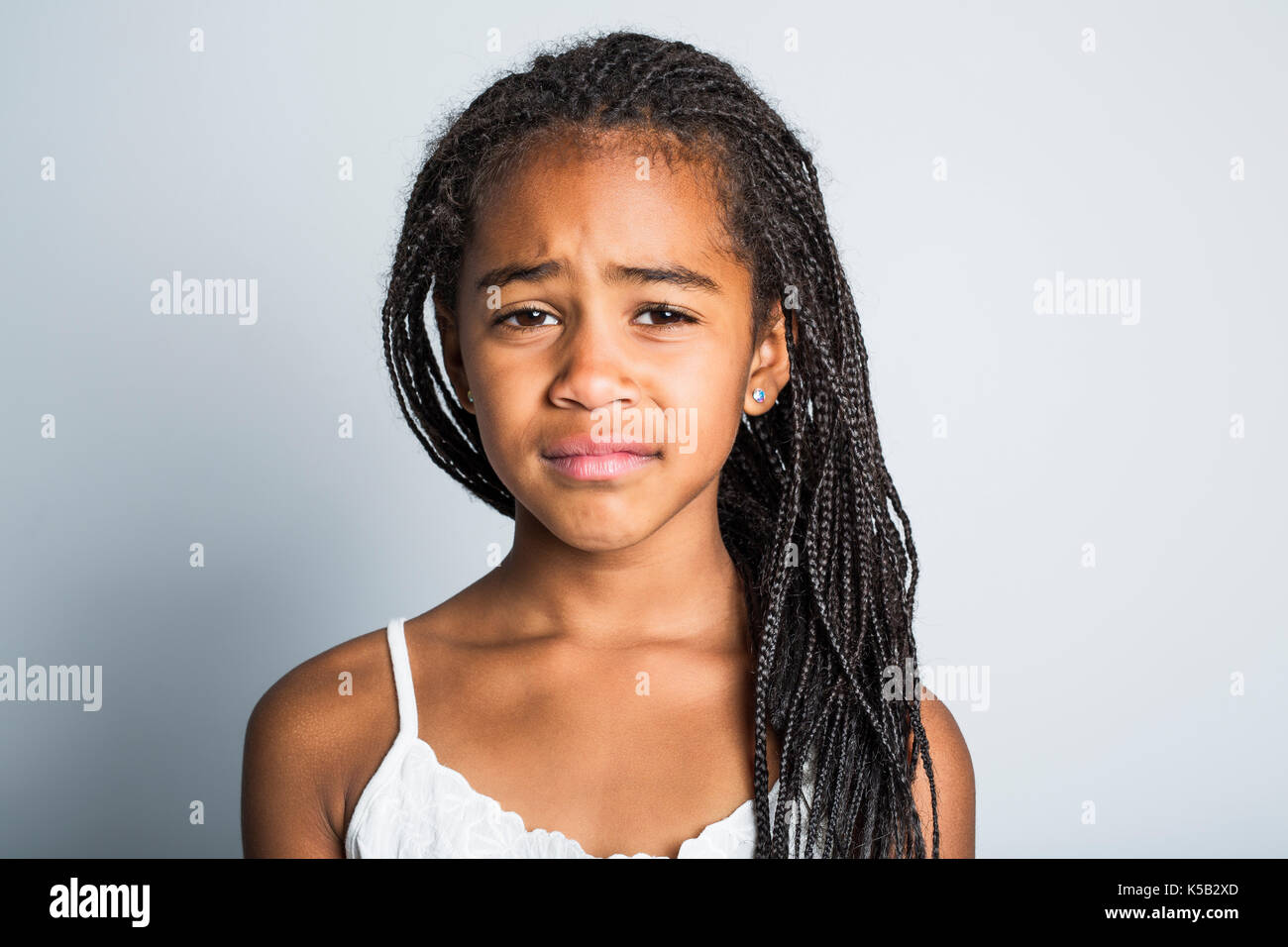 Adorable sad african little girl on studio gray background Stock Photo ...