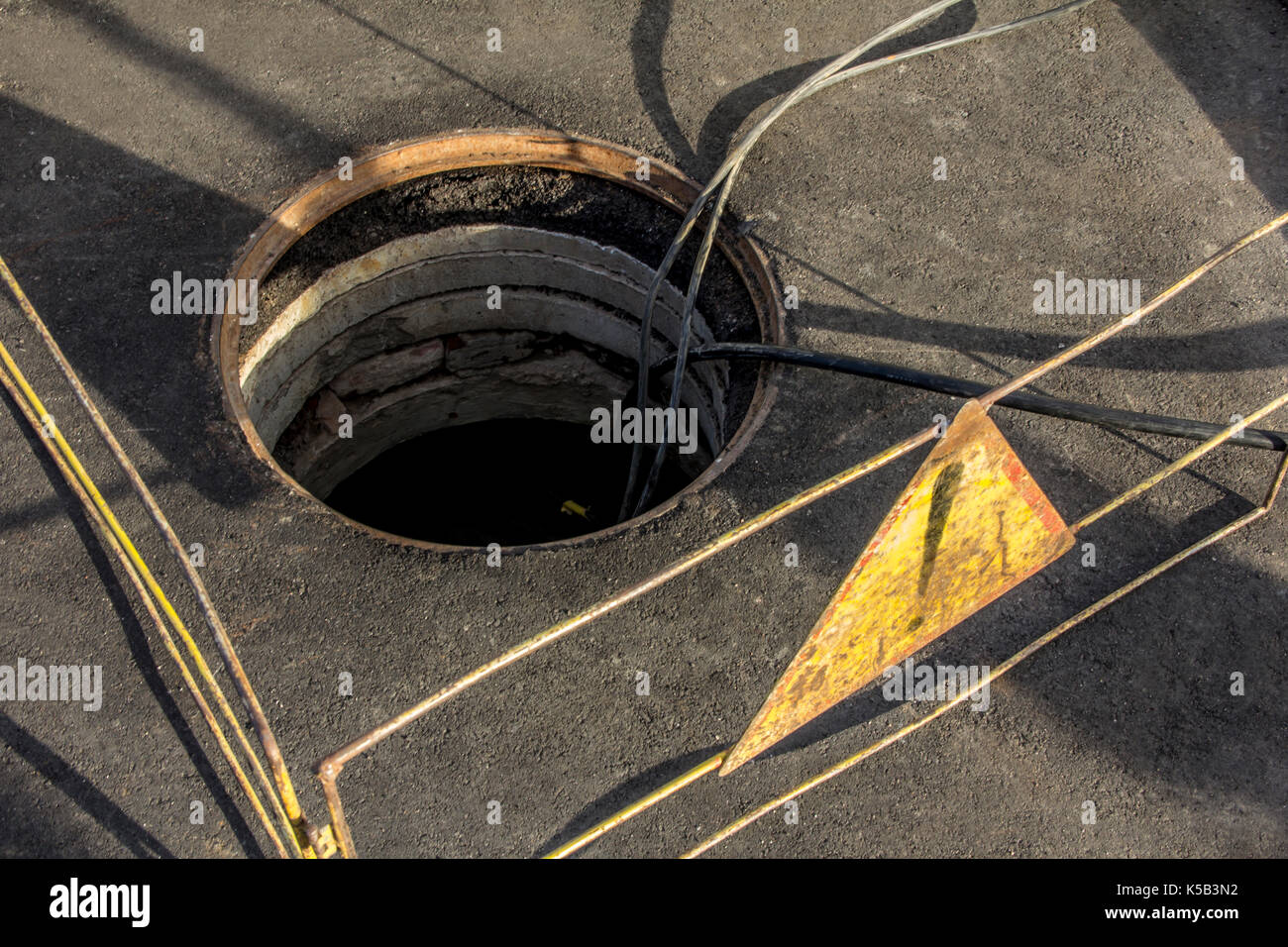 cable layout into a sewer well on the asphalted road enclosured by ...