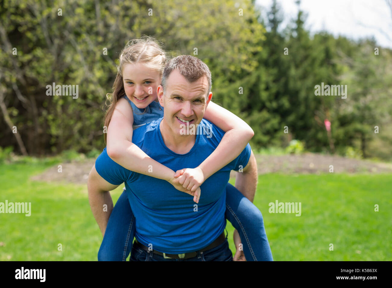 portrait of a father carrying teen girl on back at the park Stock Photo ...