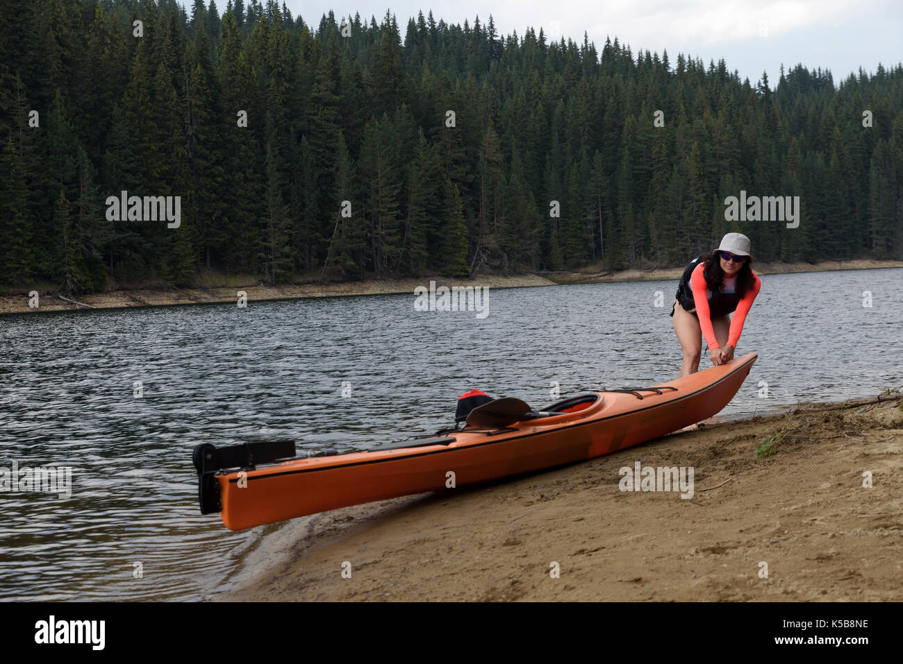Young woman pulling her kayak on a shore before the rain Stock Photo ...