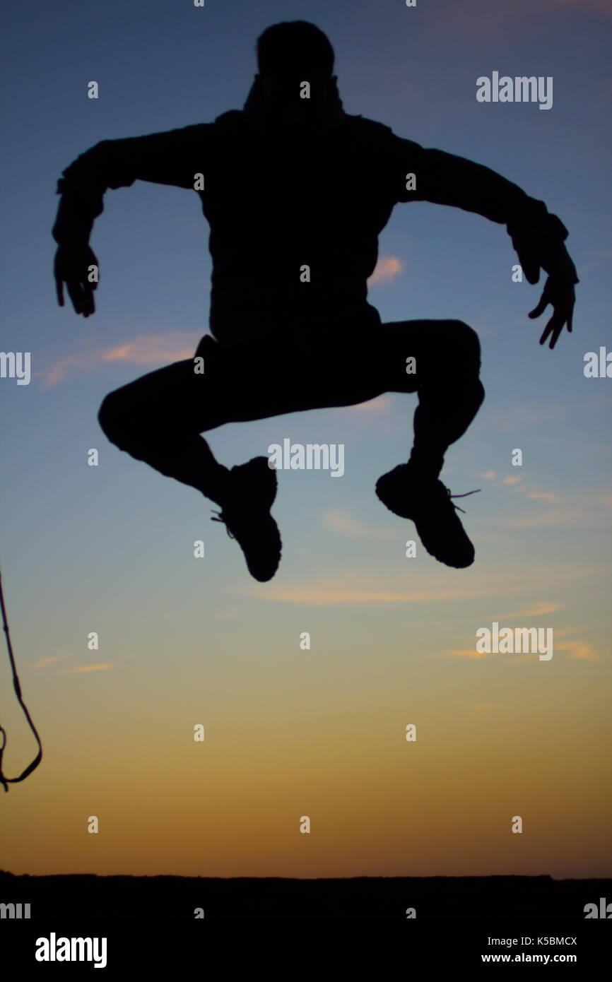 silhouette of man jumping on sunset background Stock Photo - Alamy
