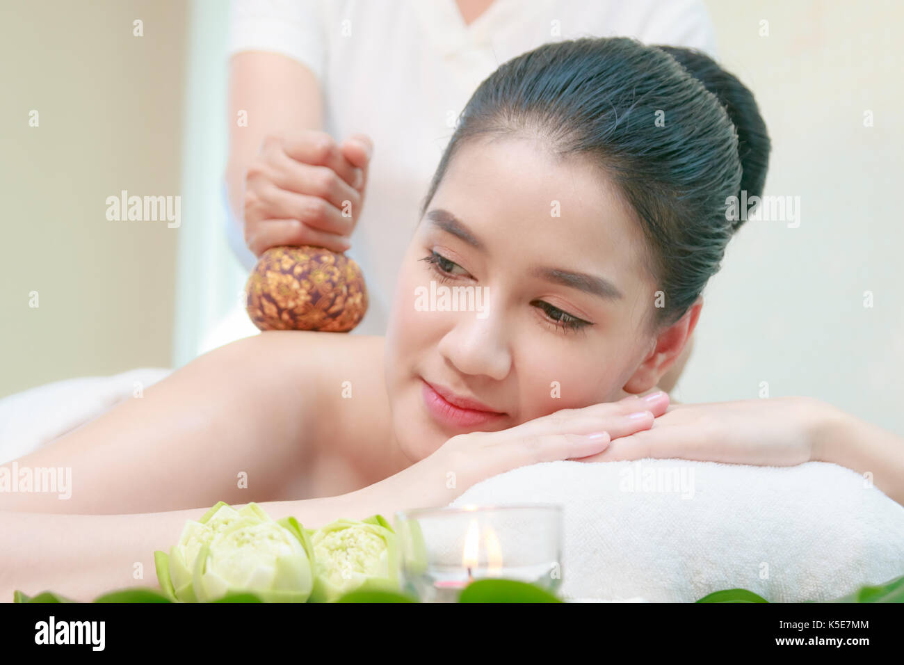 Young Asian woman having Thai herbal compress massage in spa ...