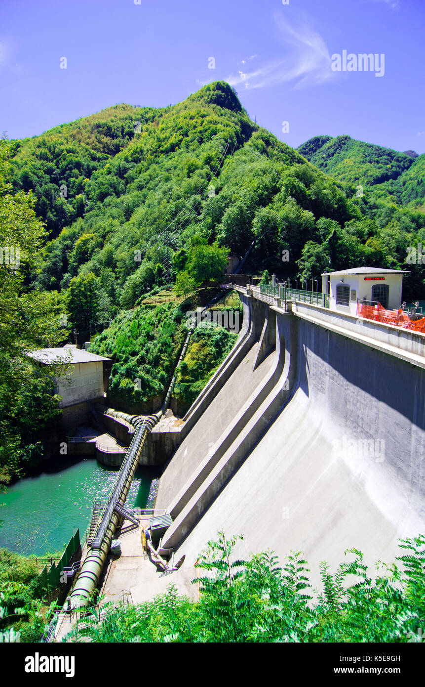 dam with blue and green water forms a small lake in the midst of ...