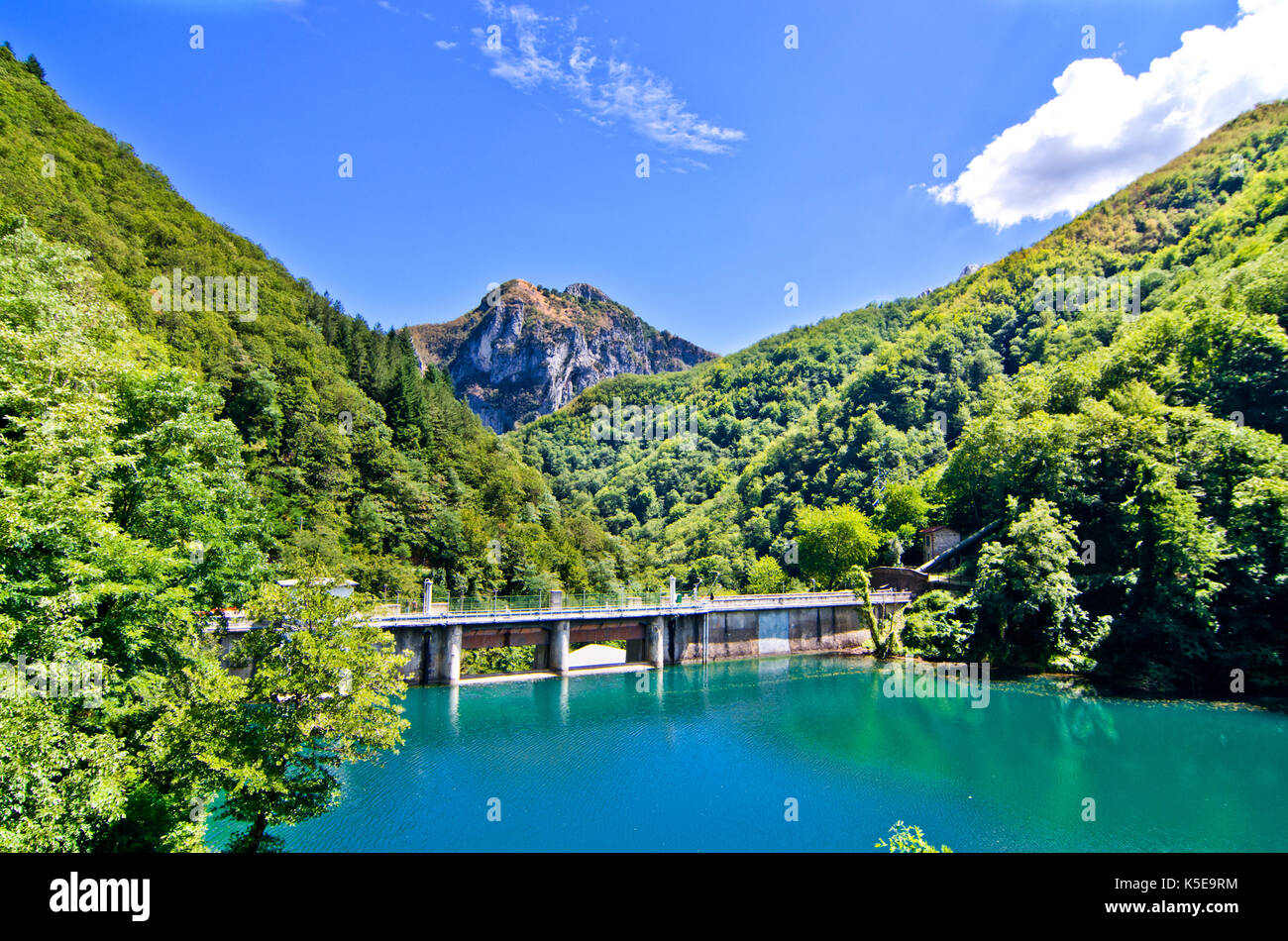 dam with blue and green water forms a small lake in the midst of ...