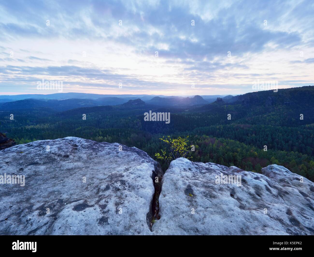 Morning view over crack sandstone edge into forest valley, daybreak Sun ...