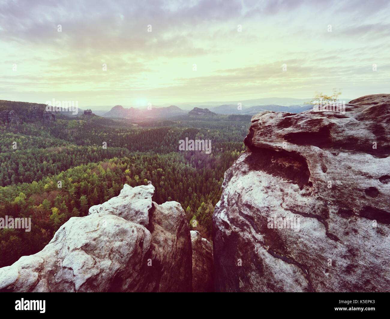 Morning view over crack sandstone edge into forest valley, daybreak Sun ...