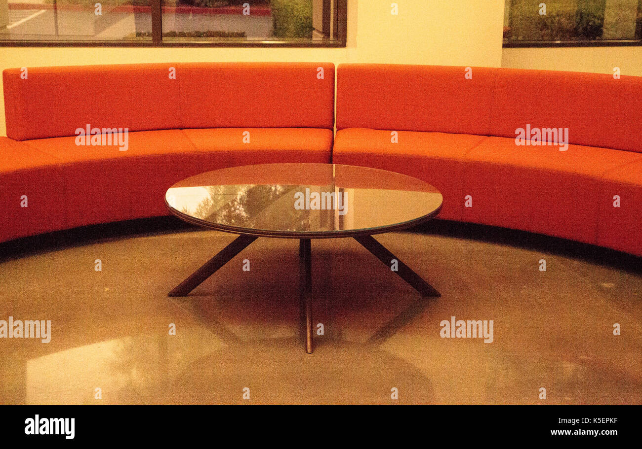 Modern curved orange couch in front of large windows with a round ...