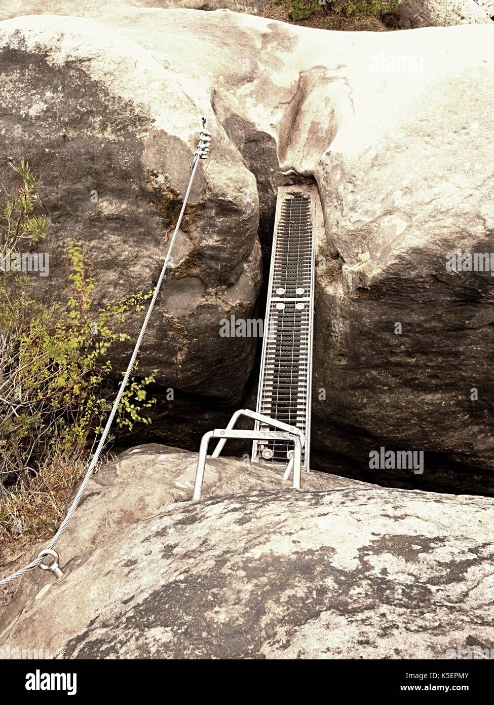 Iron ramp in rock, tourist ladder. Iron twisted rope fixed in block by ...