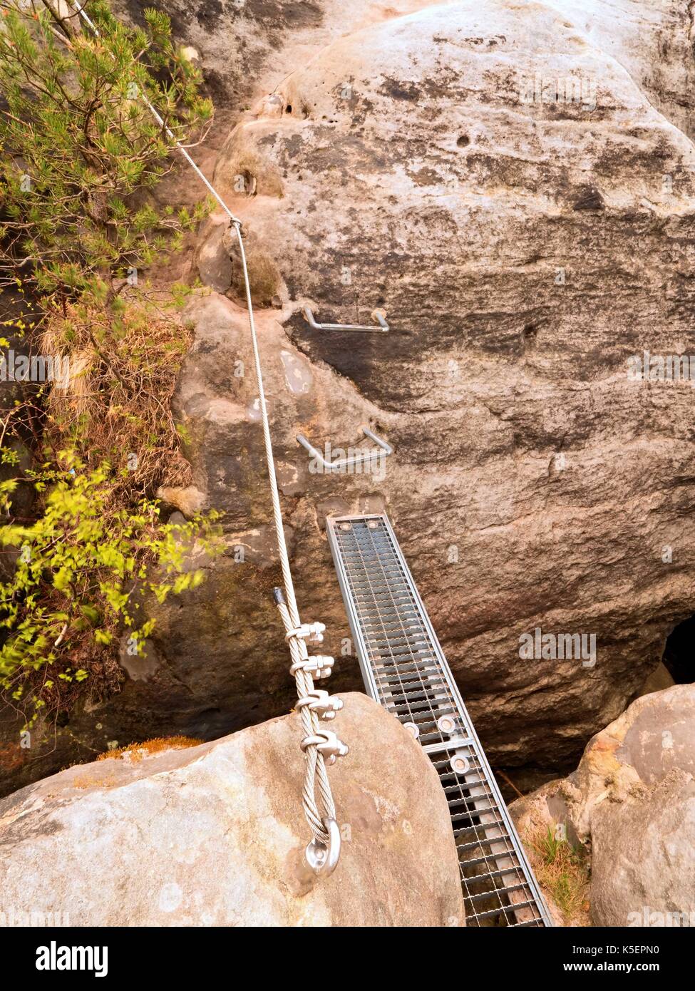 Iron ramp in rock, tourist ladder. Iron twisted rope fixed in block by ...