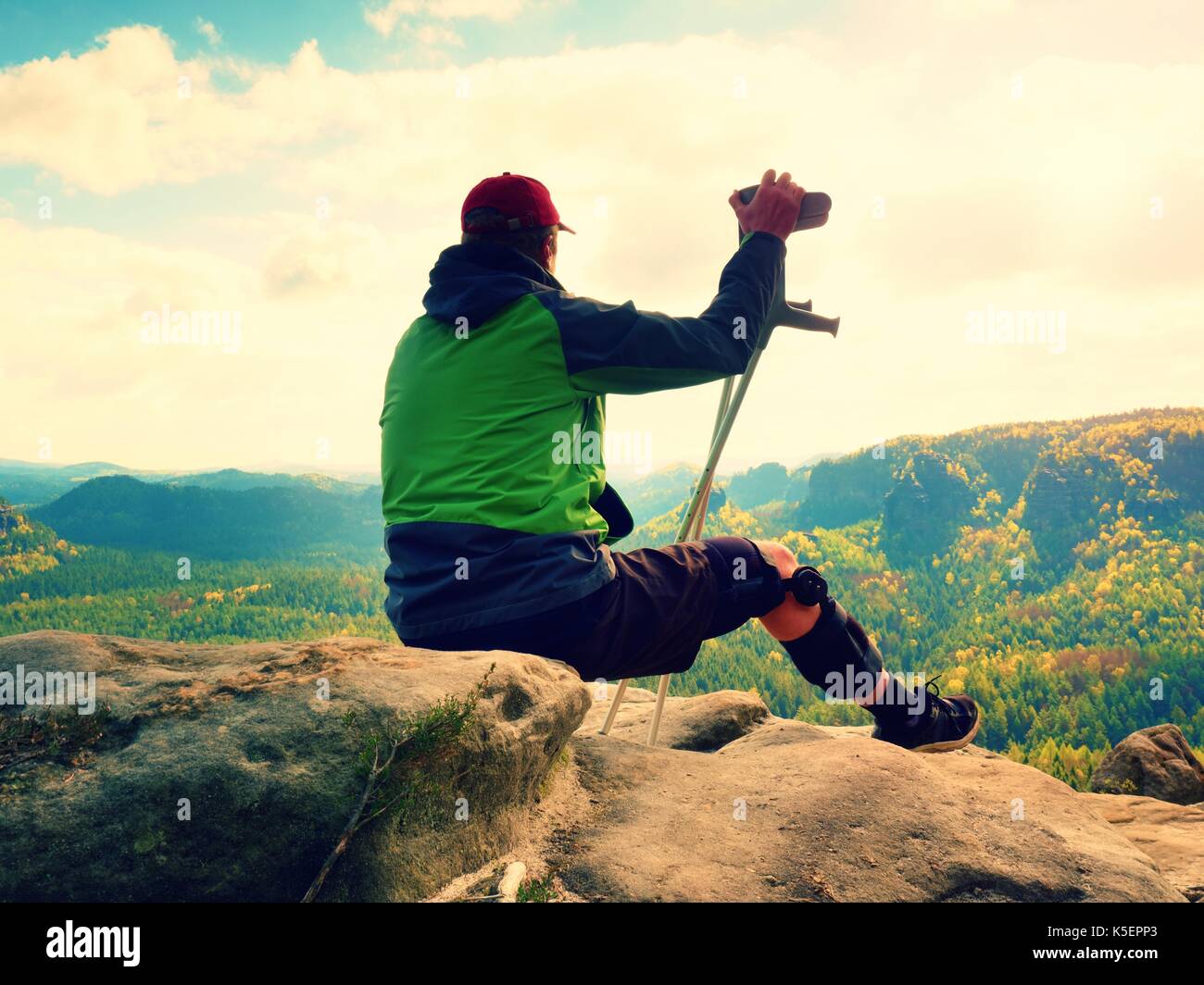 Tired man tourist sit with hurt knee in immobilizer or rock, hold ...