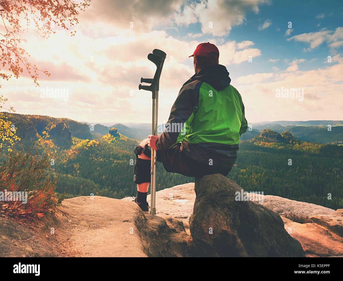 Tired man tourist sit with hurt knee in immobilizer or rock, hold ...