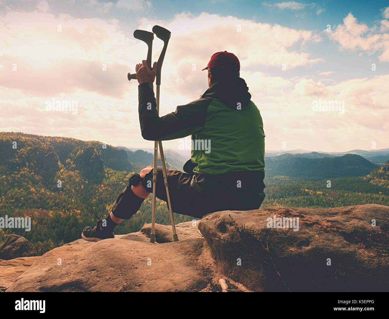 Tired man tourist sit with hurt knee in immobilizer or rock, hold ...
