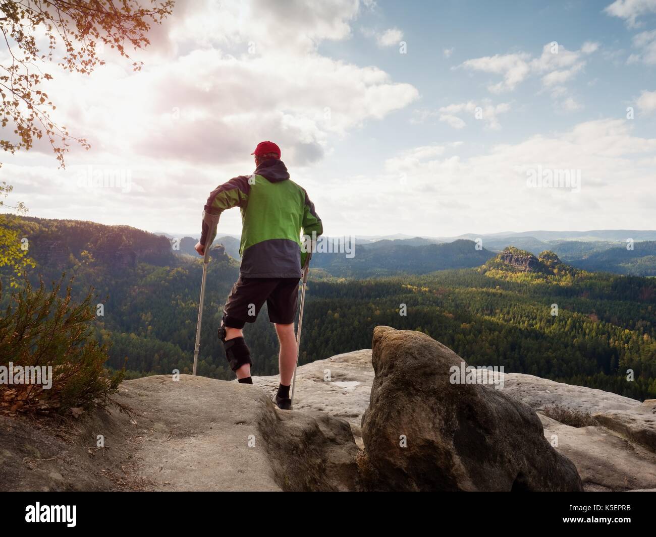 Man with forearm crutches. Hiker after hard walk achieved mountain peak ...