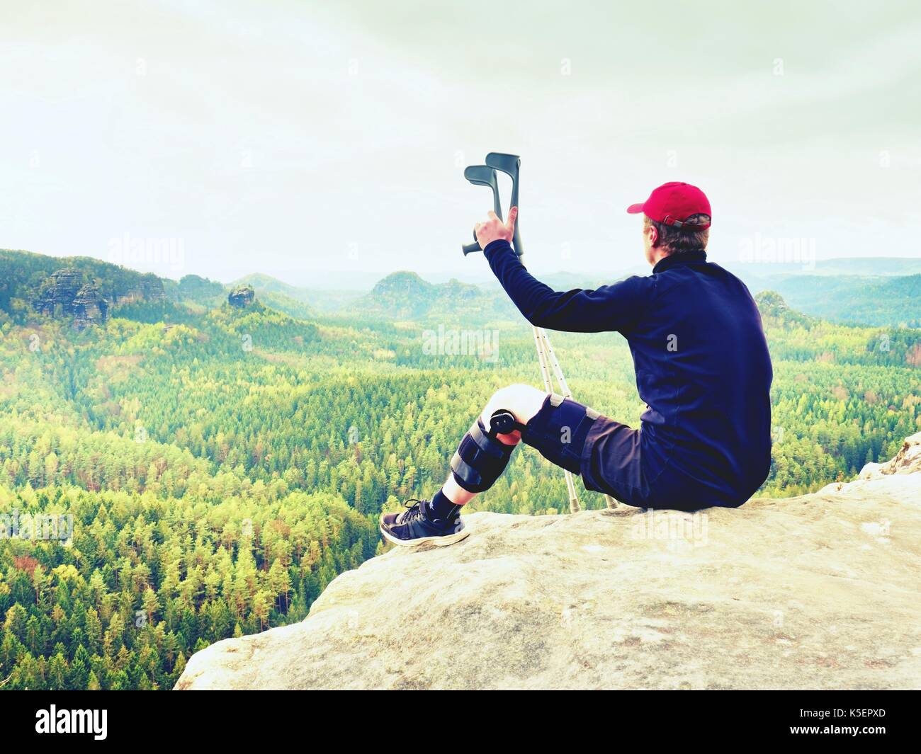 Tired hurt tourist with medicine crutches. Man with broken leg in knee ...