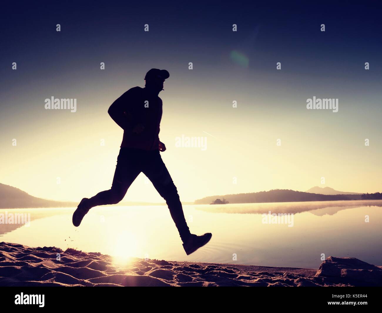 Tall fit man running fast by the sea on the beach. Powerful runner ...