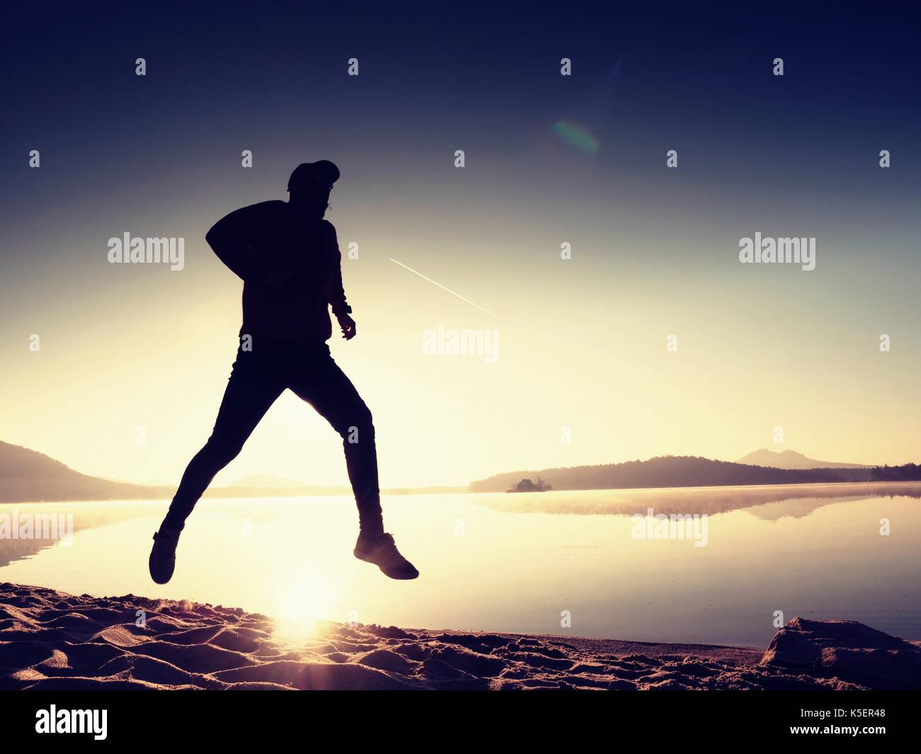 Tall fit man running fast by the sea on the beach. Powerful runner ...