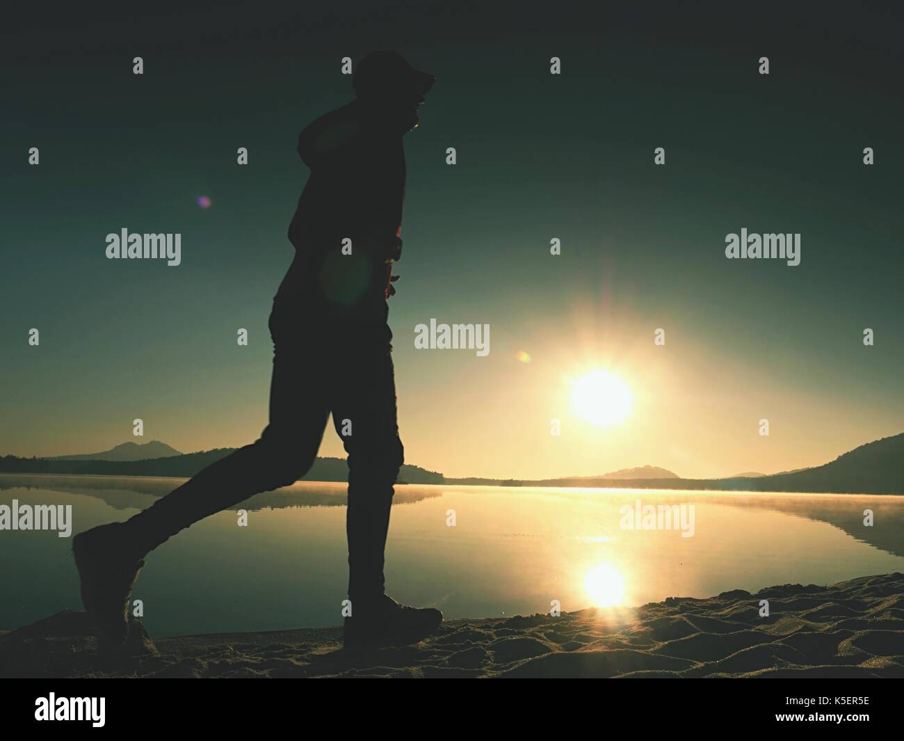 Tall fit man running fast by the sea on the beach. Powerful runner ...