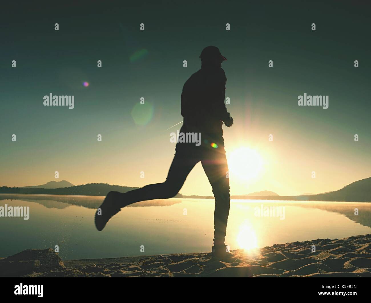 Tall fit man running fast by the sea on the beach. Powerful runner ...