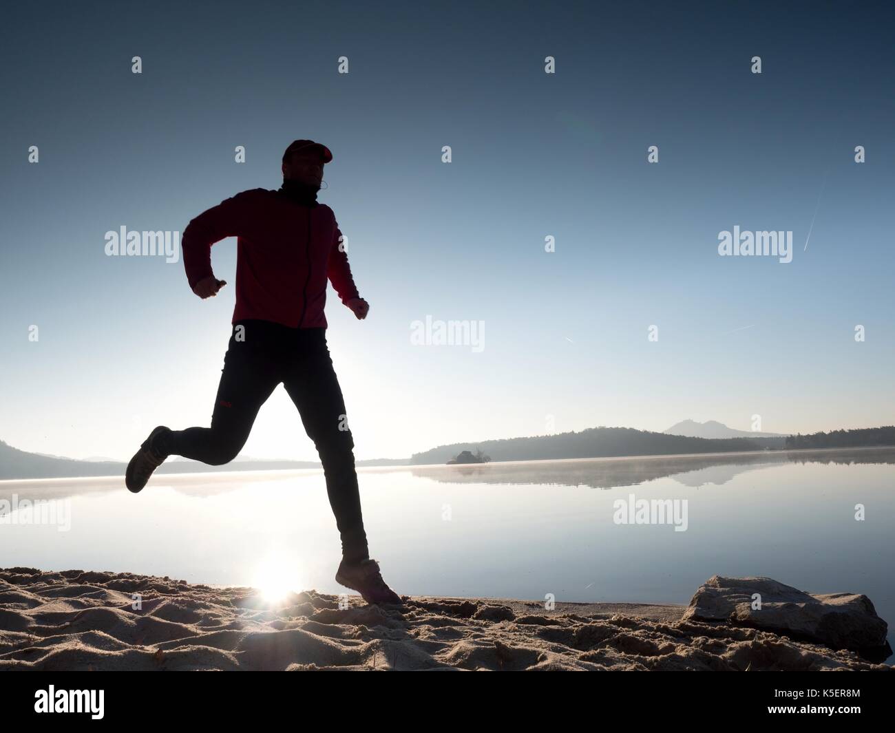 Tall fit man running fast by the sea on the beach. Powerful runner ...