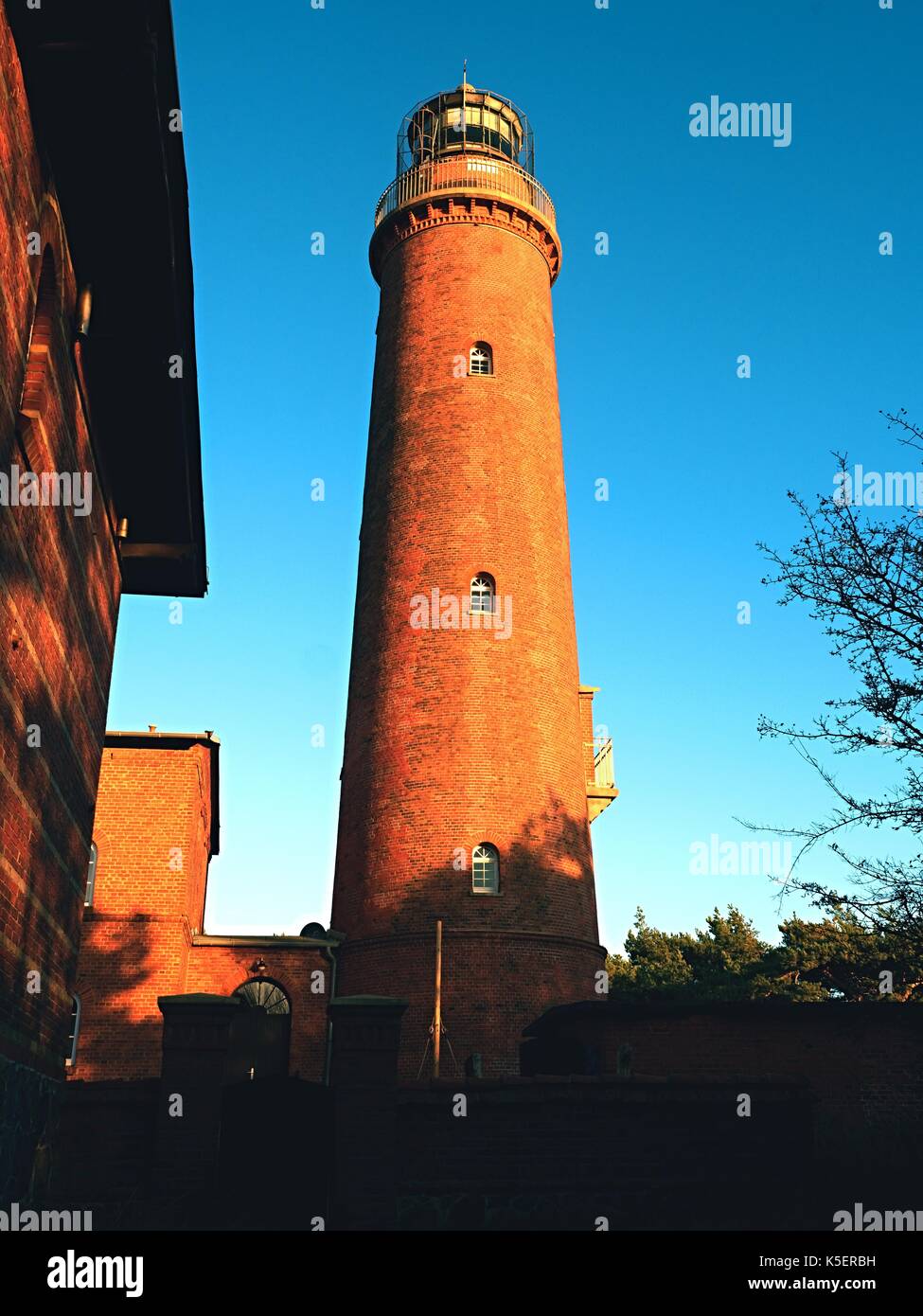 Shinning old lighthouse above houses and forest before sunset. Tower ...