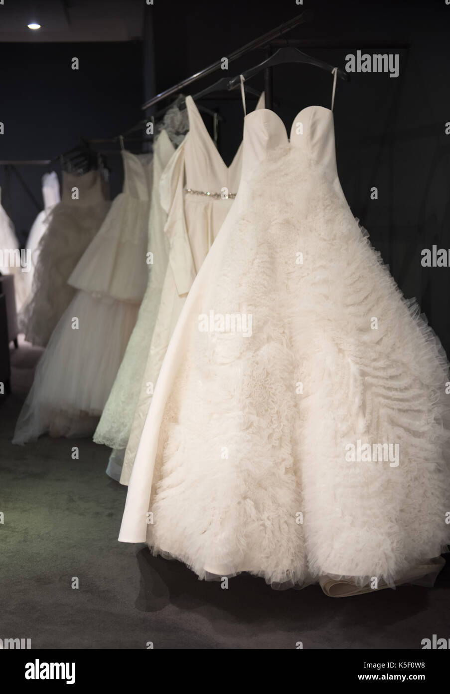 Selection of white wedding dresses or ball gowns on display hanging on ...