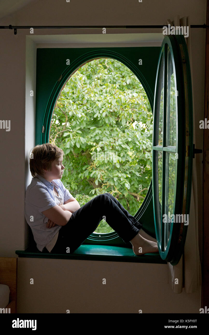 young boy sitting in a window Stock Photo - Alamy