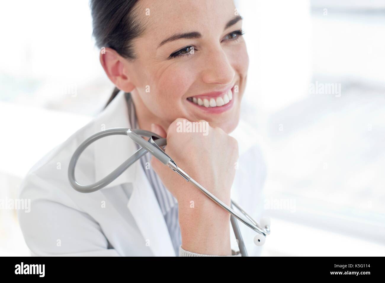 Female doctor holding stethoscope, smiling Stock Photo - Alamy