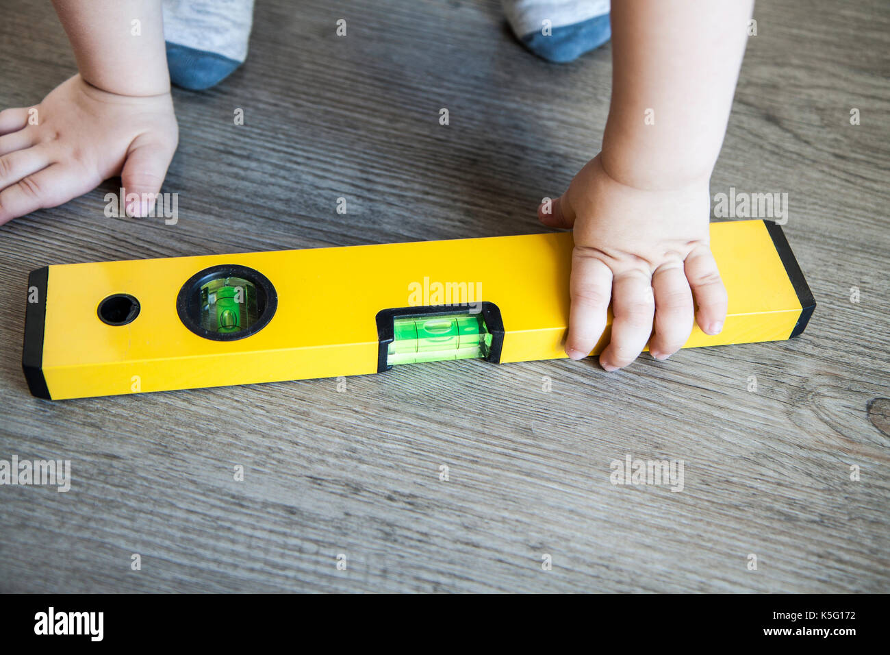 spirit level in young boy hand - child with waterlevel, wood floor ...